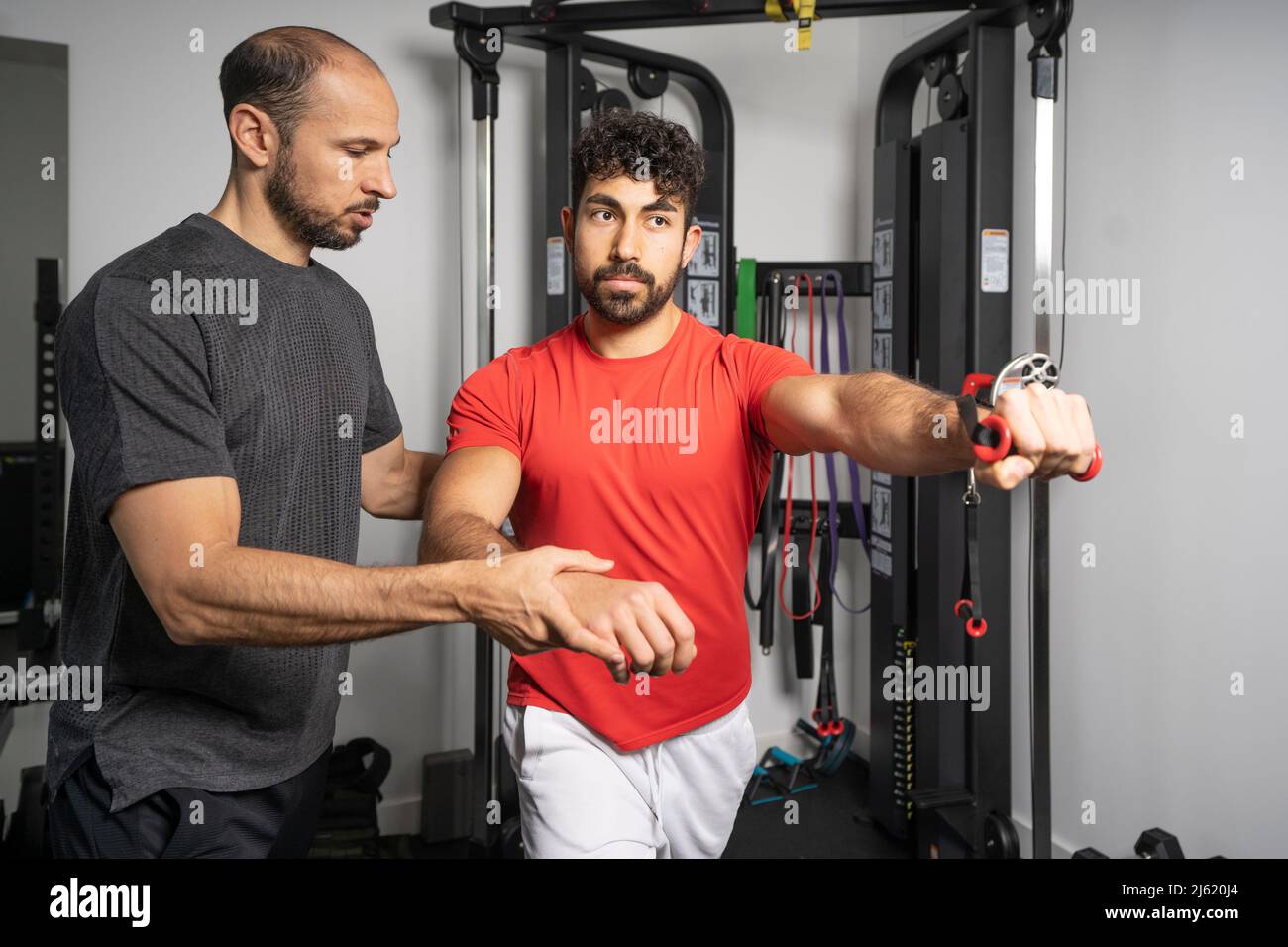 Fitness instructor giving training to athlete at gym Stock Photo - Alamy