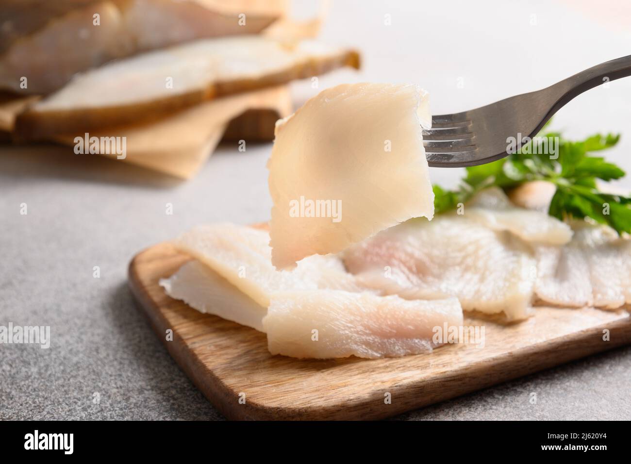 Smoked halibut slices on gray background. Man eating delicacy fish ...