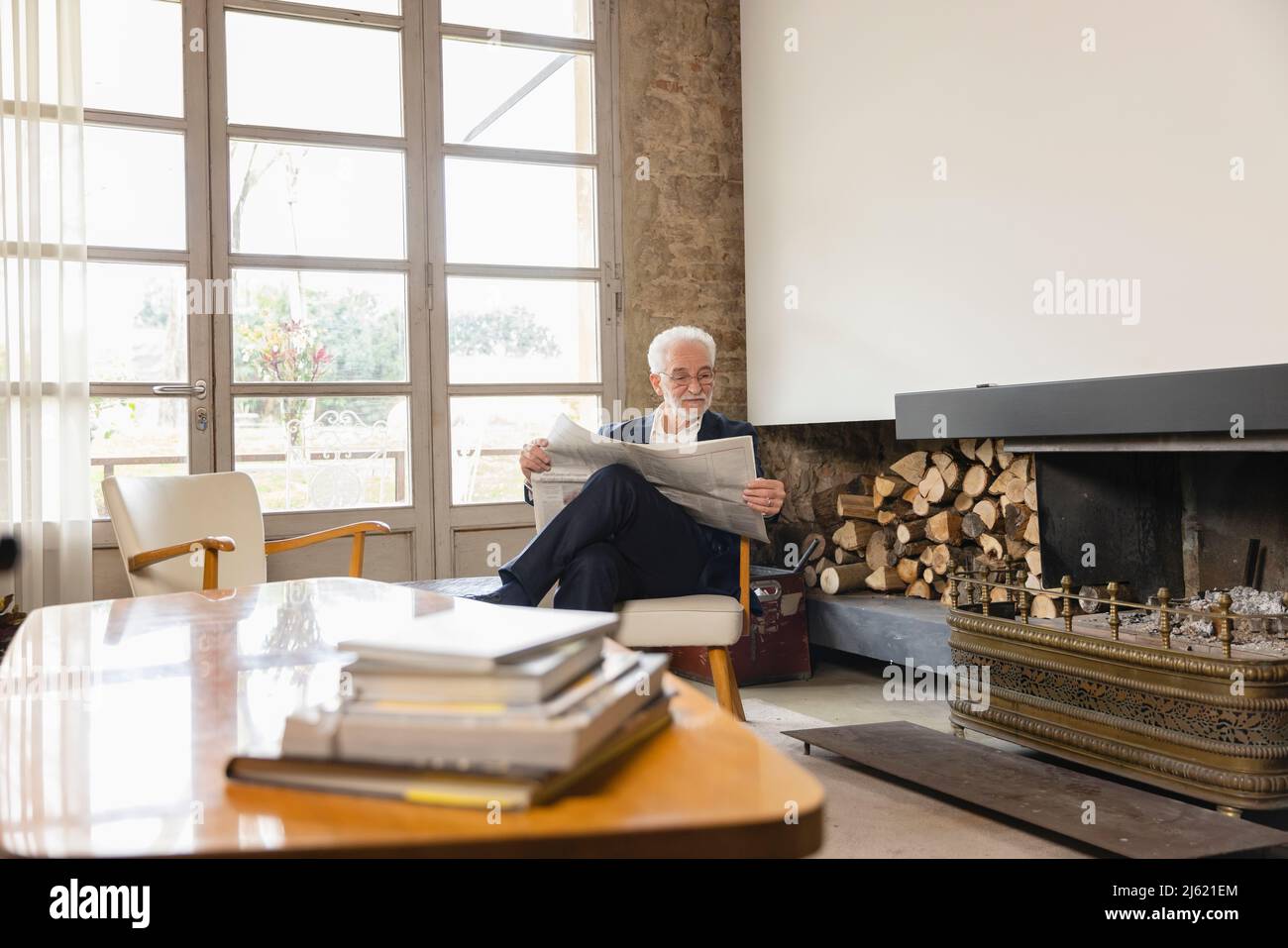 Man reading newspaper sitting on chair in living room at home Stock ...