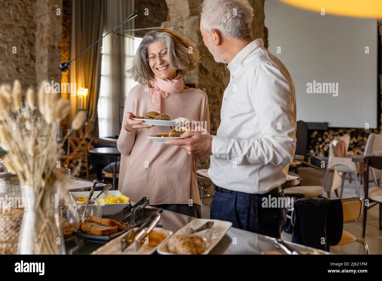 Happy senior couple enjoying breakfast at buffet in boutique hotel ...