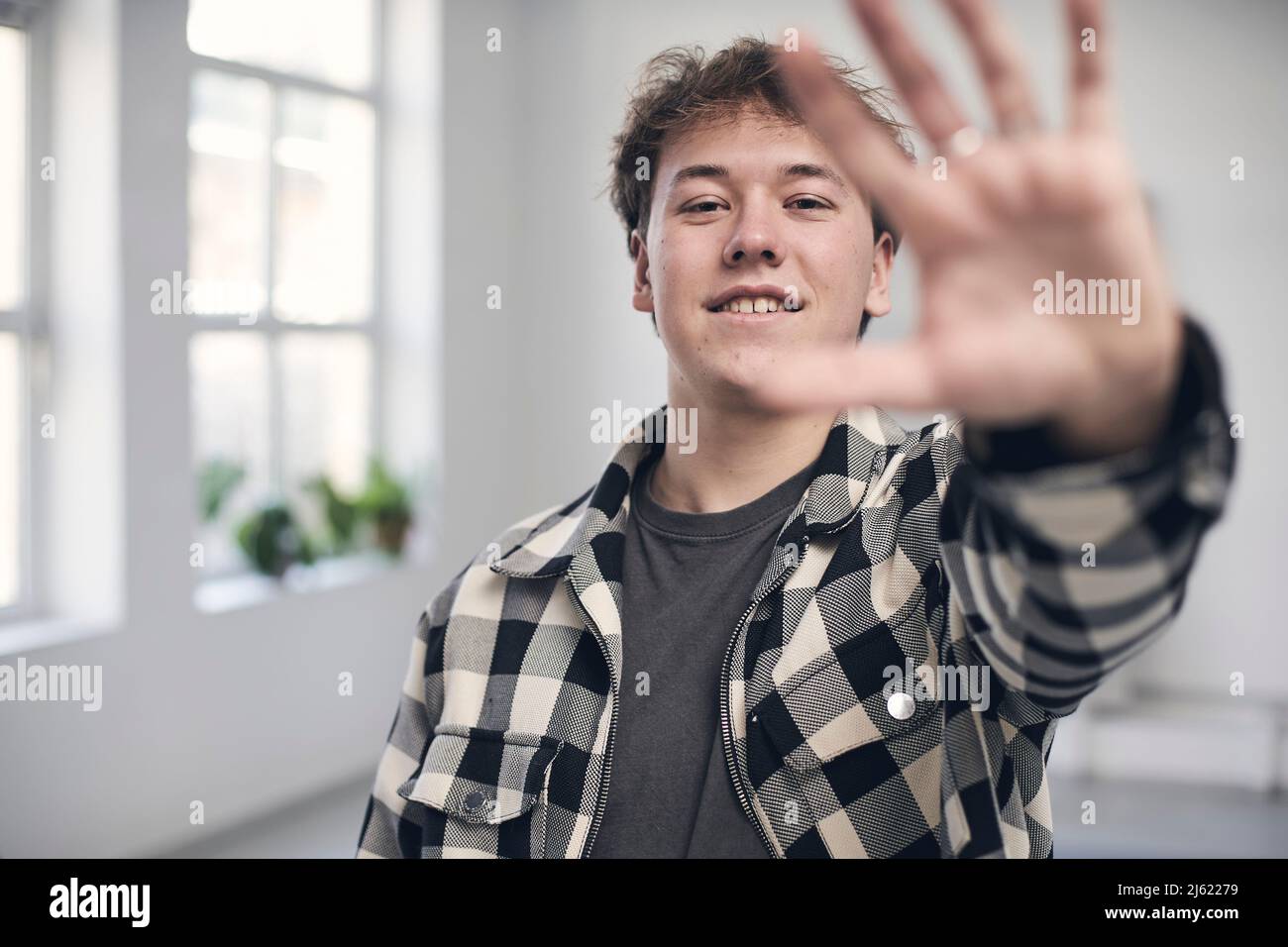 Smiling young man raising hand Stock Photo - Alamy