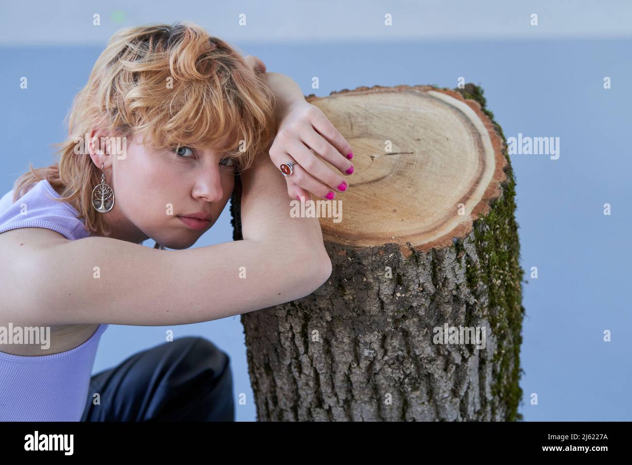 Beautiful woman with blond hair leaning on log Stock Photo - Alamy