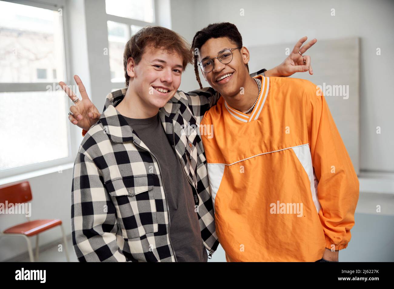 Smiling young men gesturing peace sign Stock Photo - Alamy