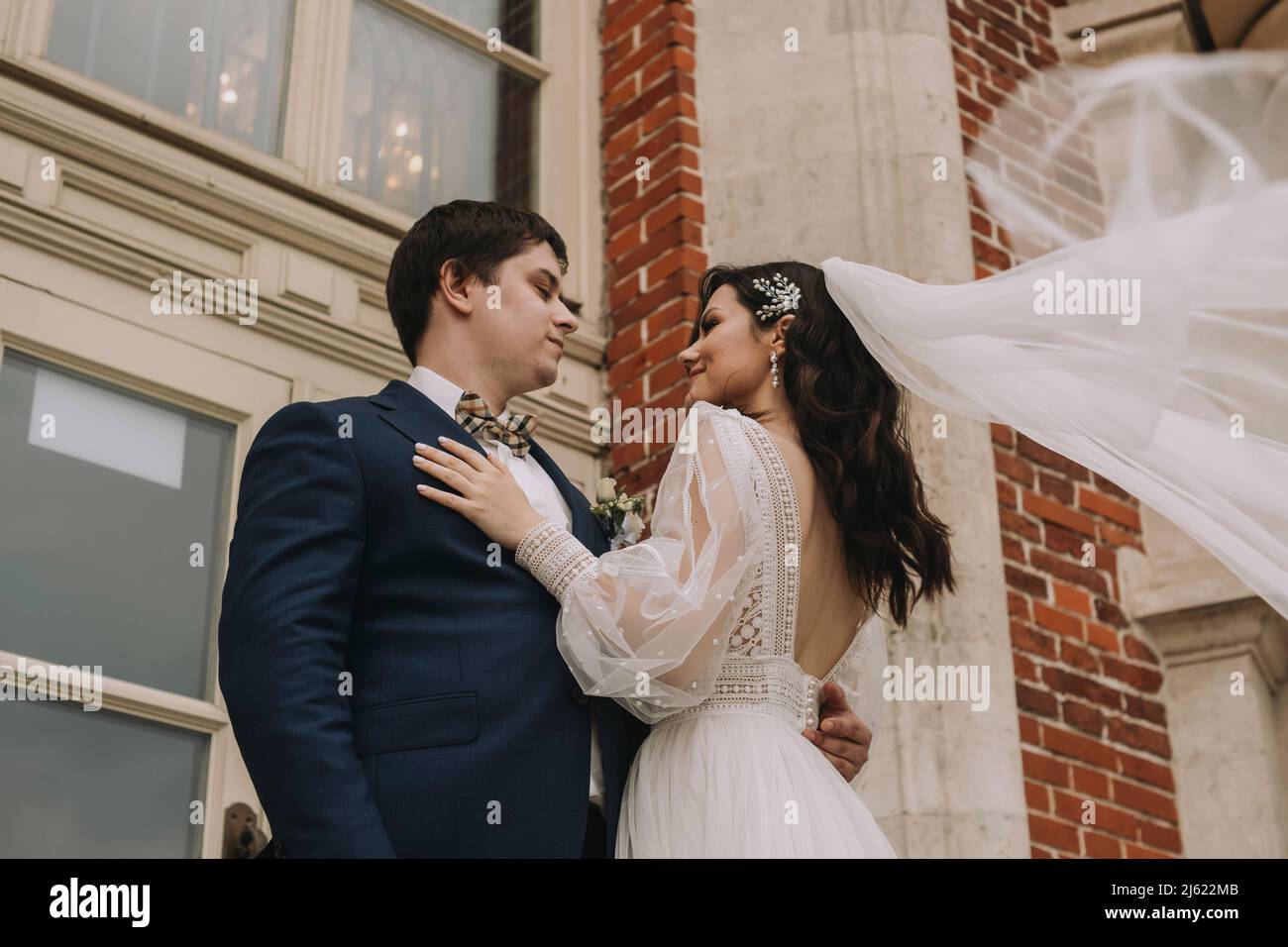 Smiling bride embracing groom in front of building Stock Photo - Alamy