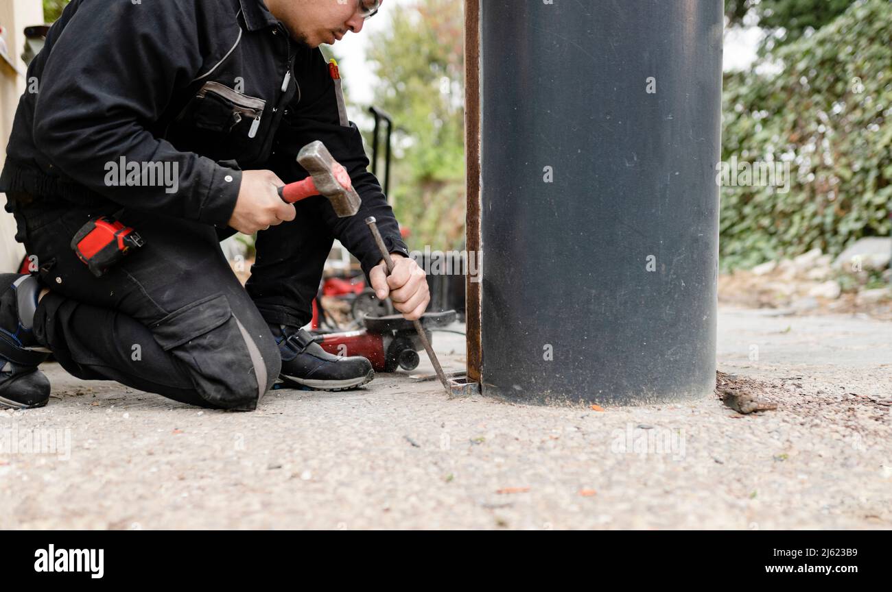 Construction worker with hammer working by metal pillar Stock Photo - Alamy