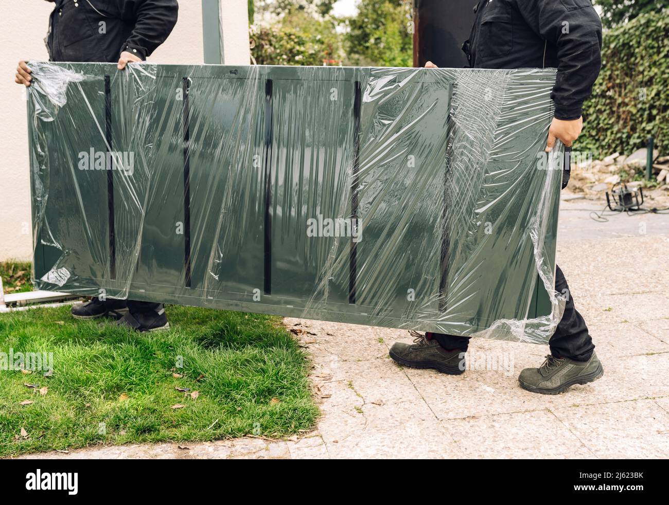 Construction workers carrying metal gate wrapped with plastic at ...