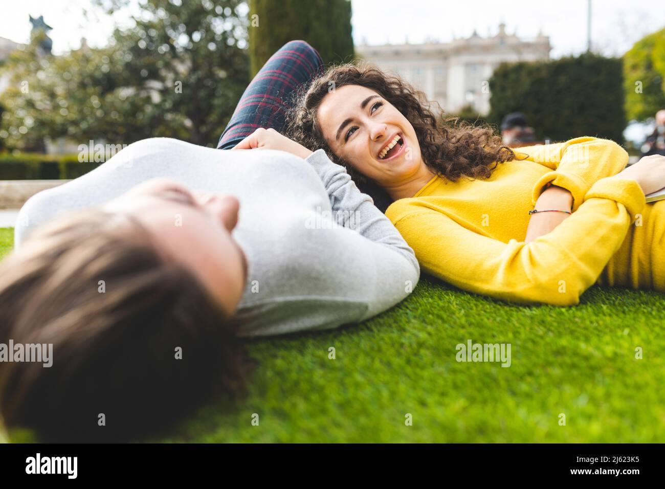 Cheerful young woman lying down with friend at park Stock Photo - Alamy