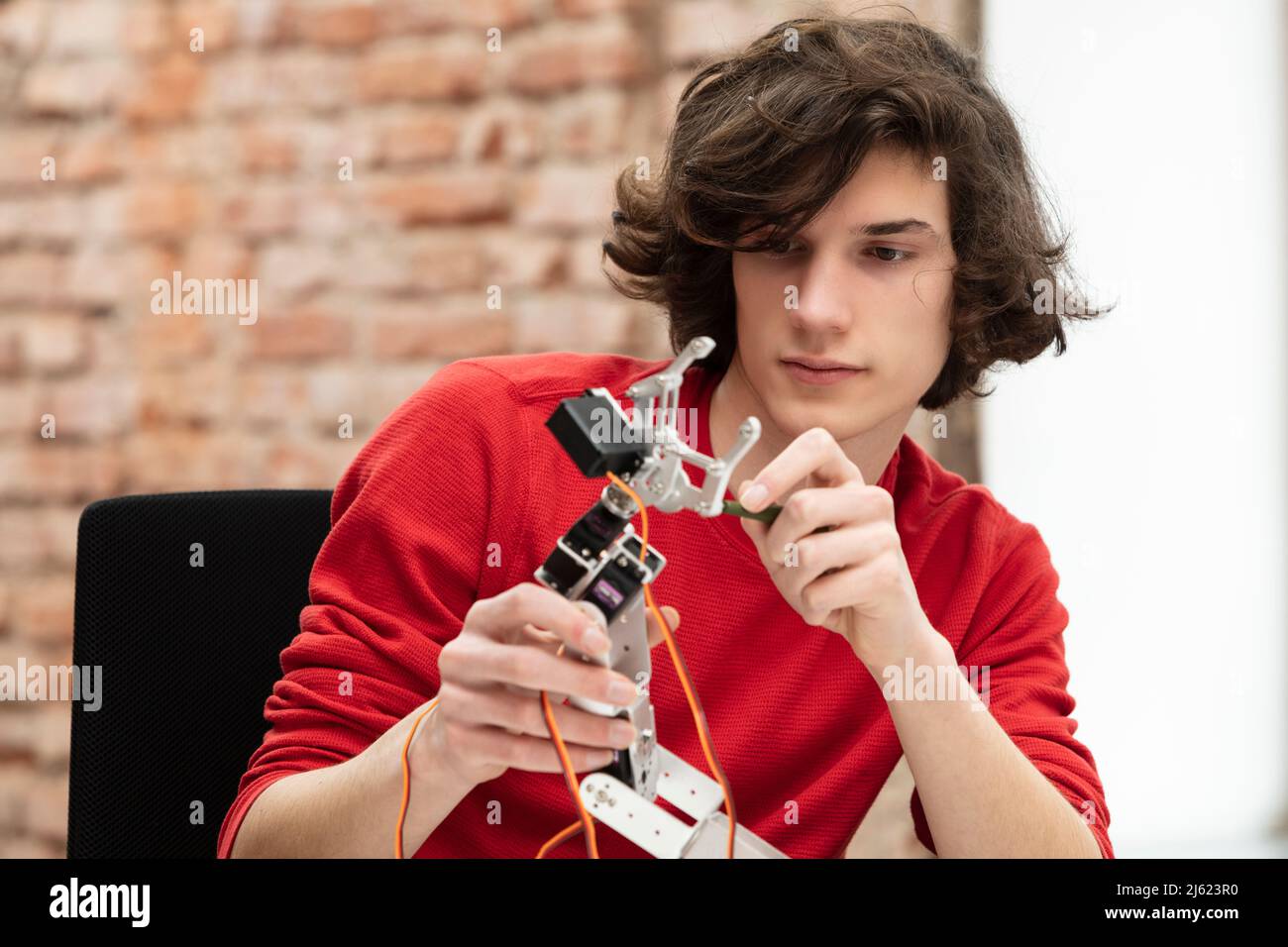 Teenage boy working on small robotic arm Stock Photo - Alamy