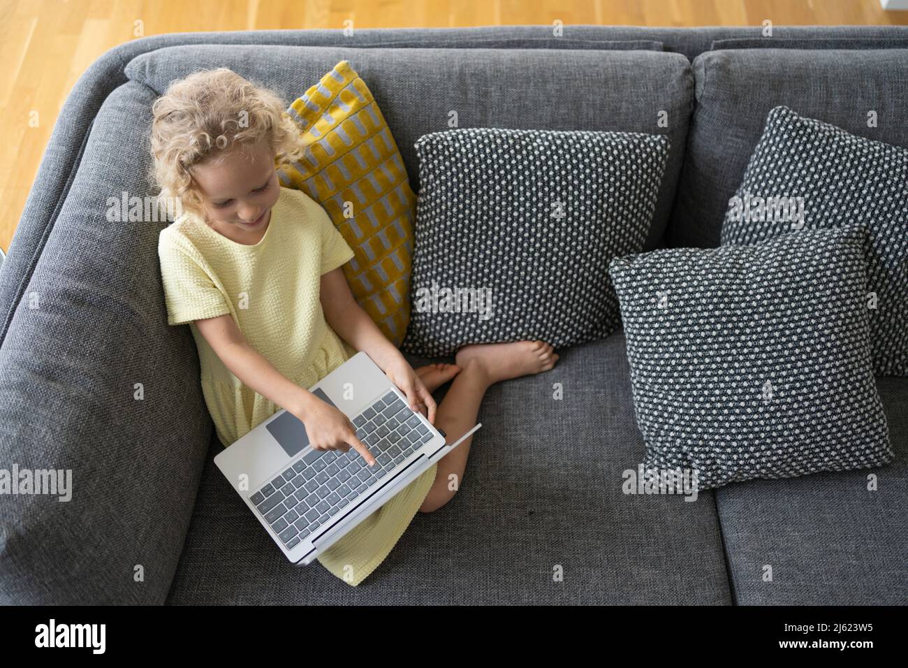 Girl with laptop sitting on sofa at home Stock Photo - Alamy