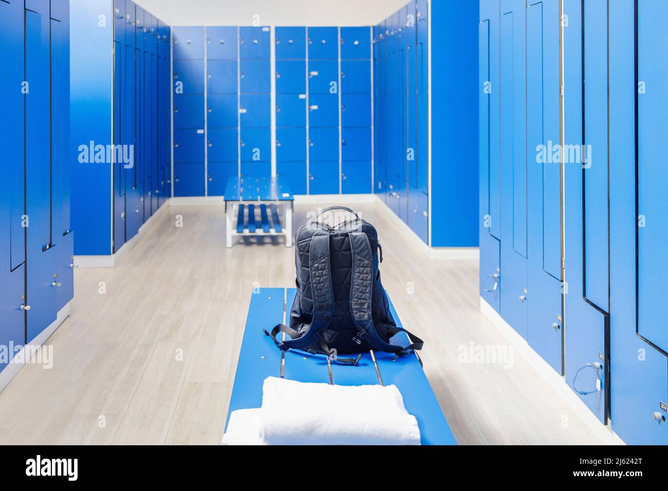 Backpack on bench in empty locker room at gym Stock Photo - Alamy