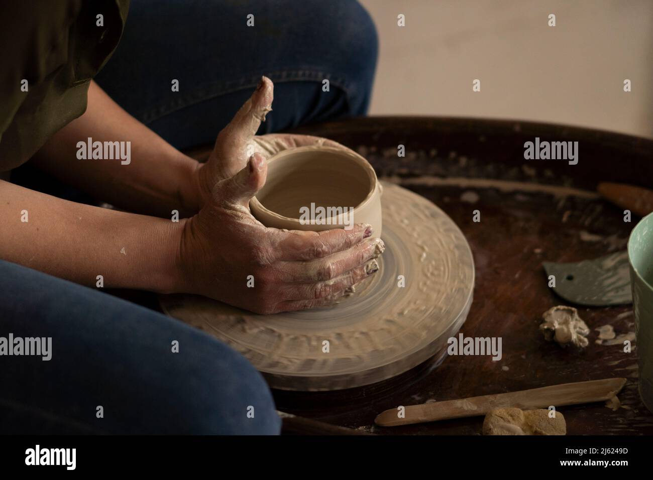 Craftsperson making pot with clay on pottery wheel at workshop Stock ...