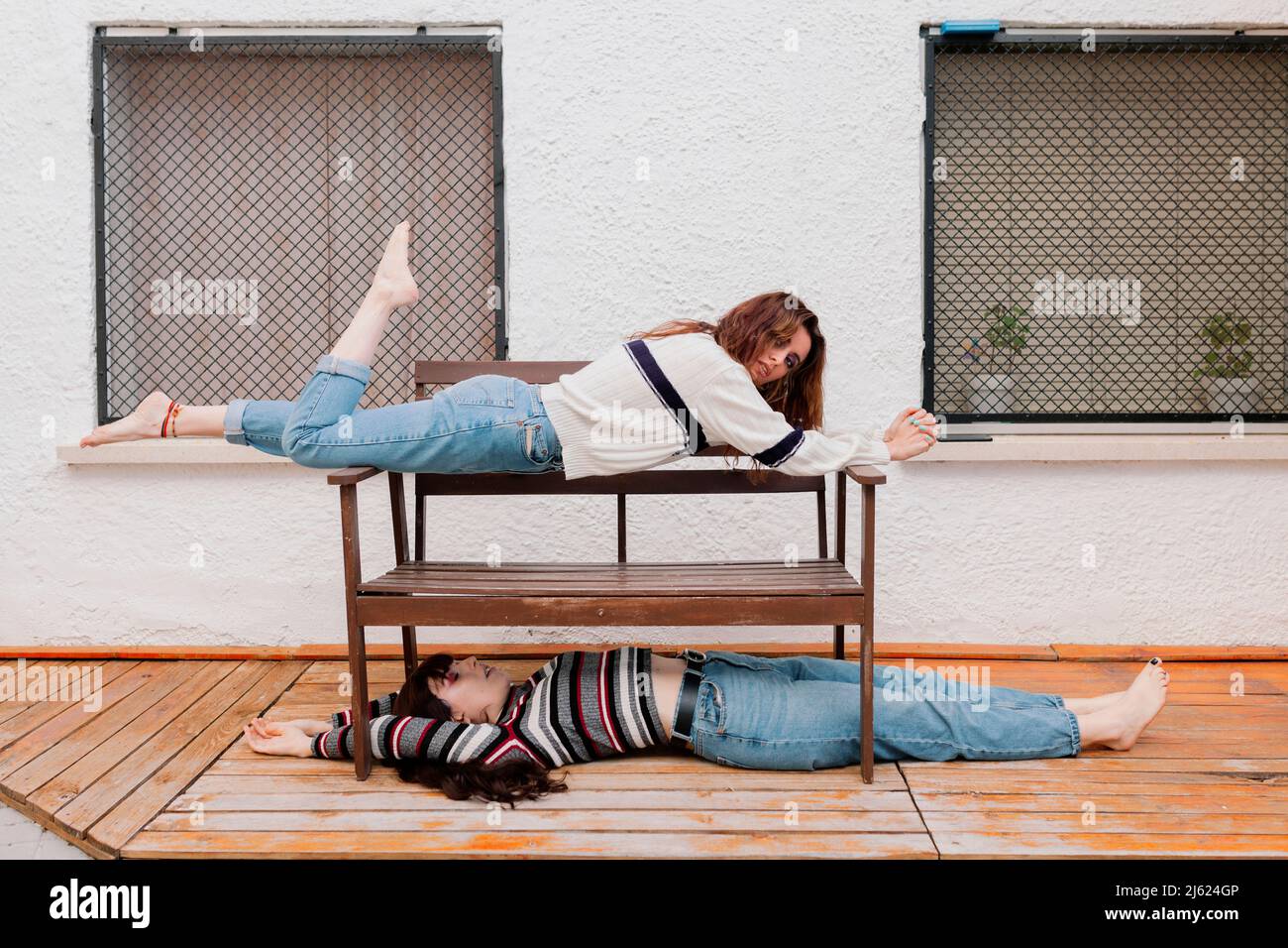 Woman lying on bench over friend at back yard Stock Photo - Alamy