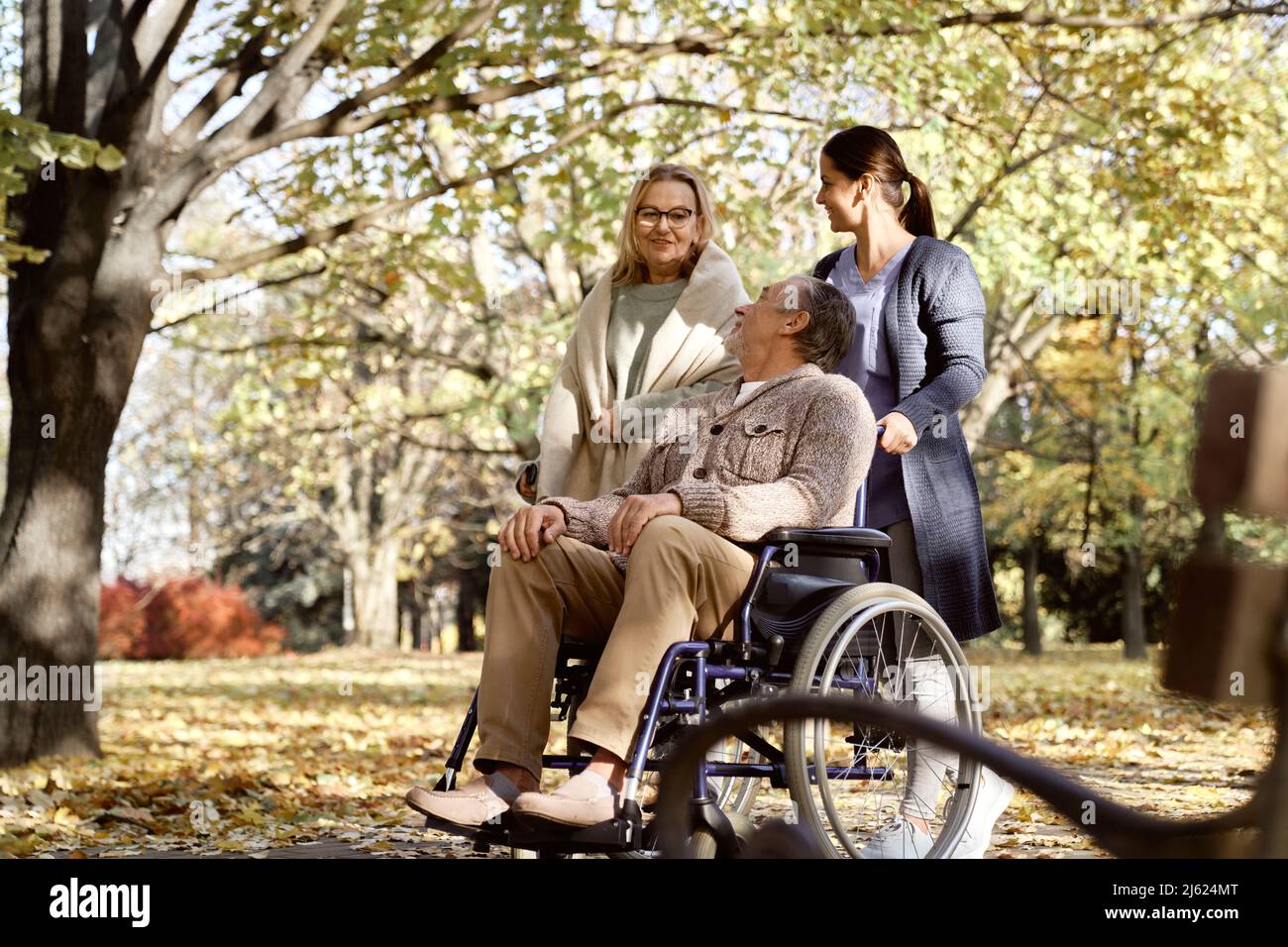 Smiling disabled man with nurse looking at senior woman talking at park ...
