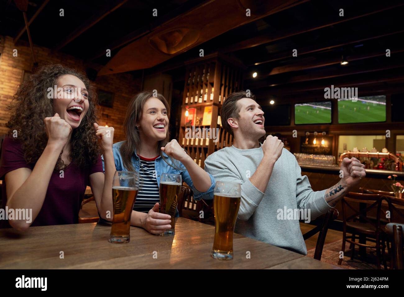 Cheerful soccer fans having beer and watching a match together in a pub ...