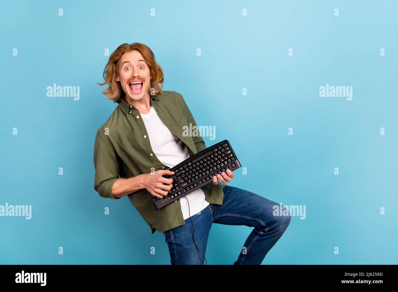 Portrait of attractive funky cheerful guy playing keyboard like guitar ...