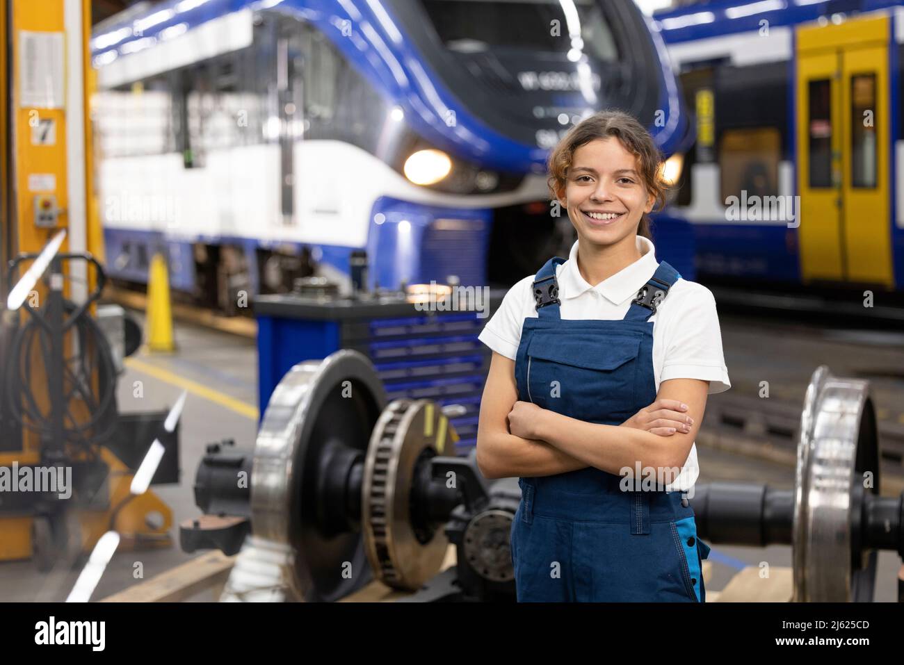 Smiling young trainee standing with arms crossed in warehouse at ...