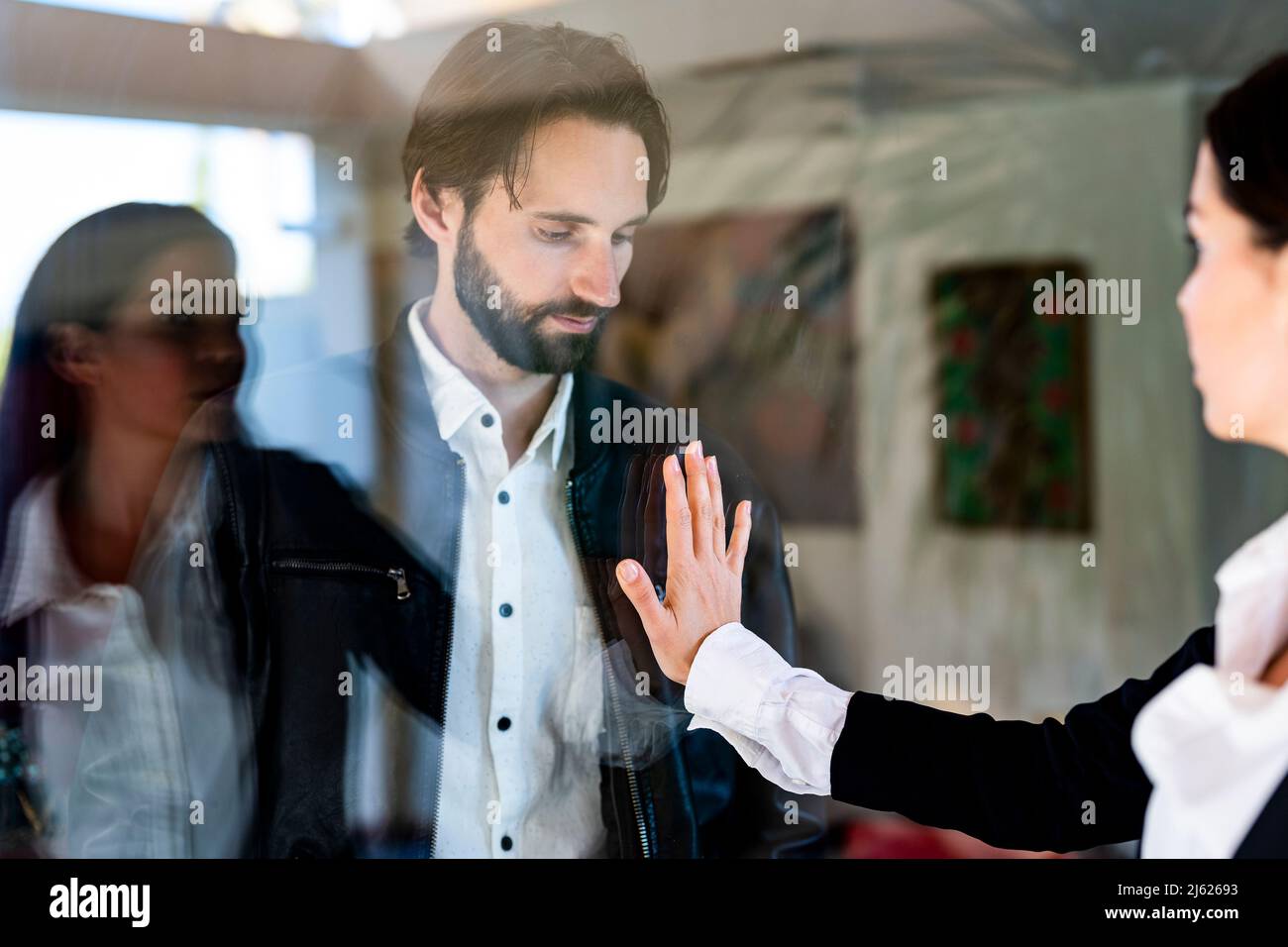Woman touching man separated through glass pane Stock Photo - Alamy
