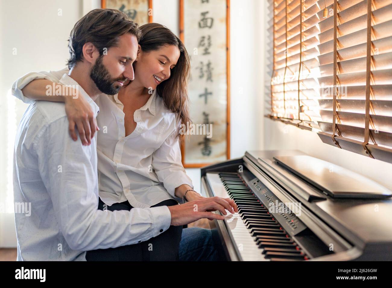 Couple playing piano sitting next to each other Stock Photo - Alamy