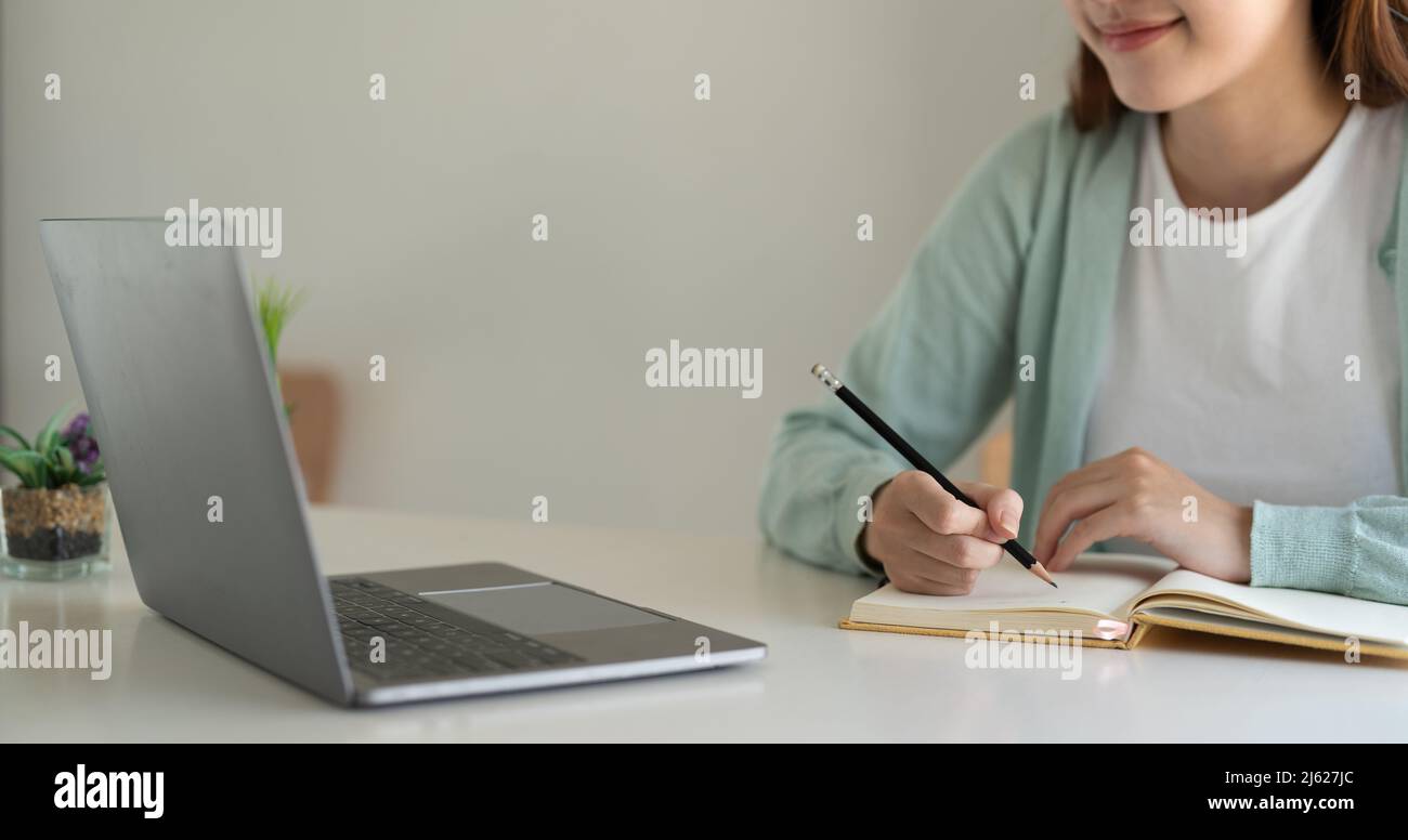 Young asian woman writing making list taking notes in notepad working ...