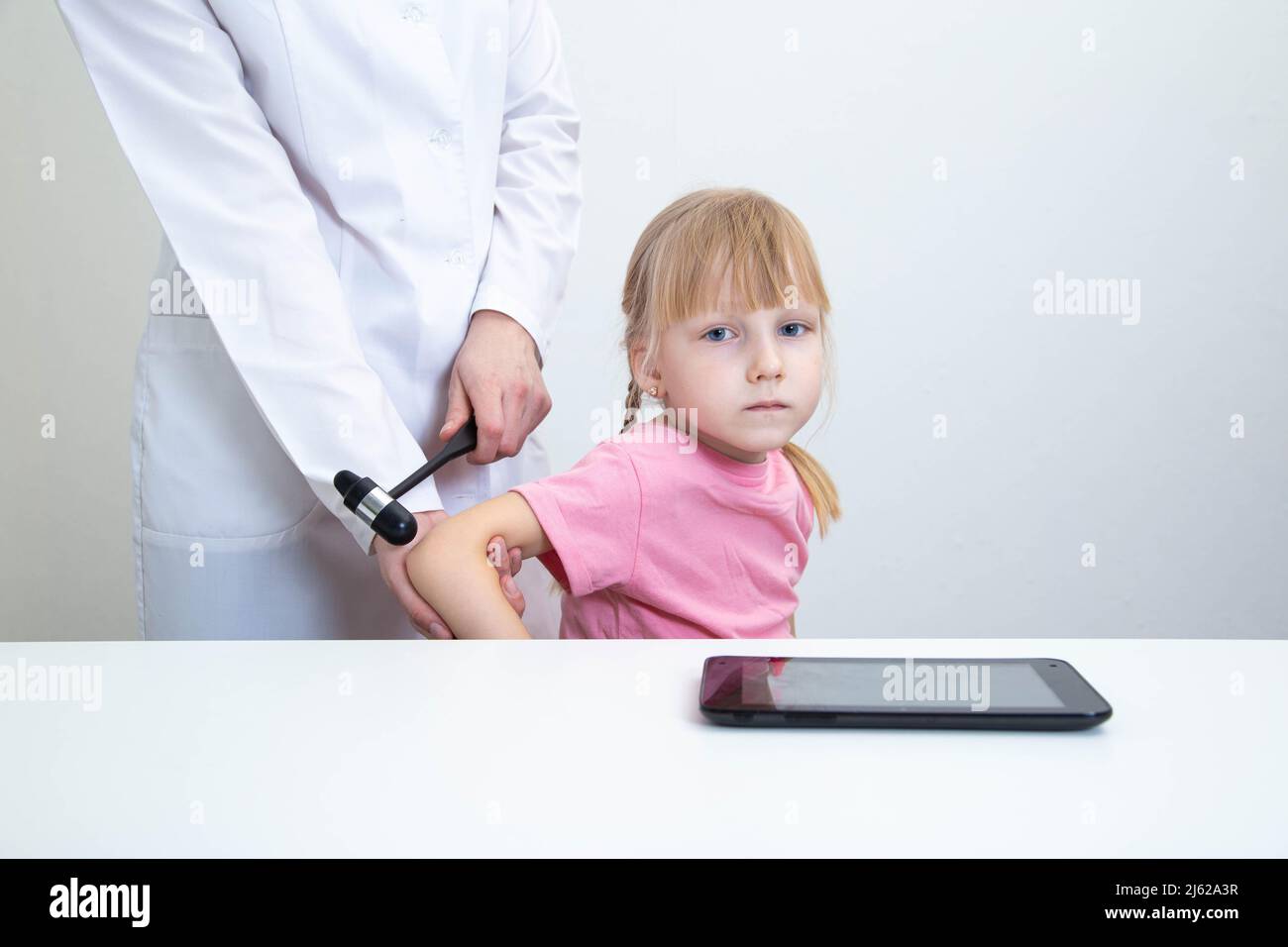 Doctor neurologist checks triceps reflex in a girl age 5 years patient ...