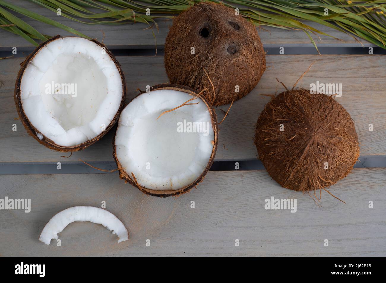 Split coconuts on wooden background with branches Stock Photo - Alamy
