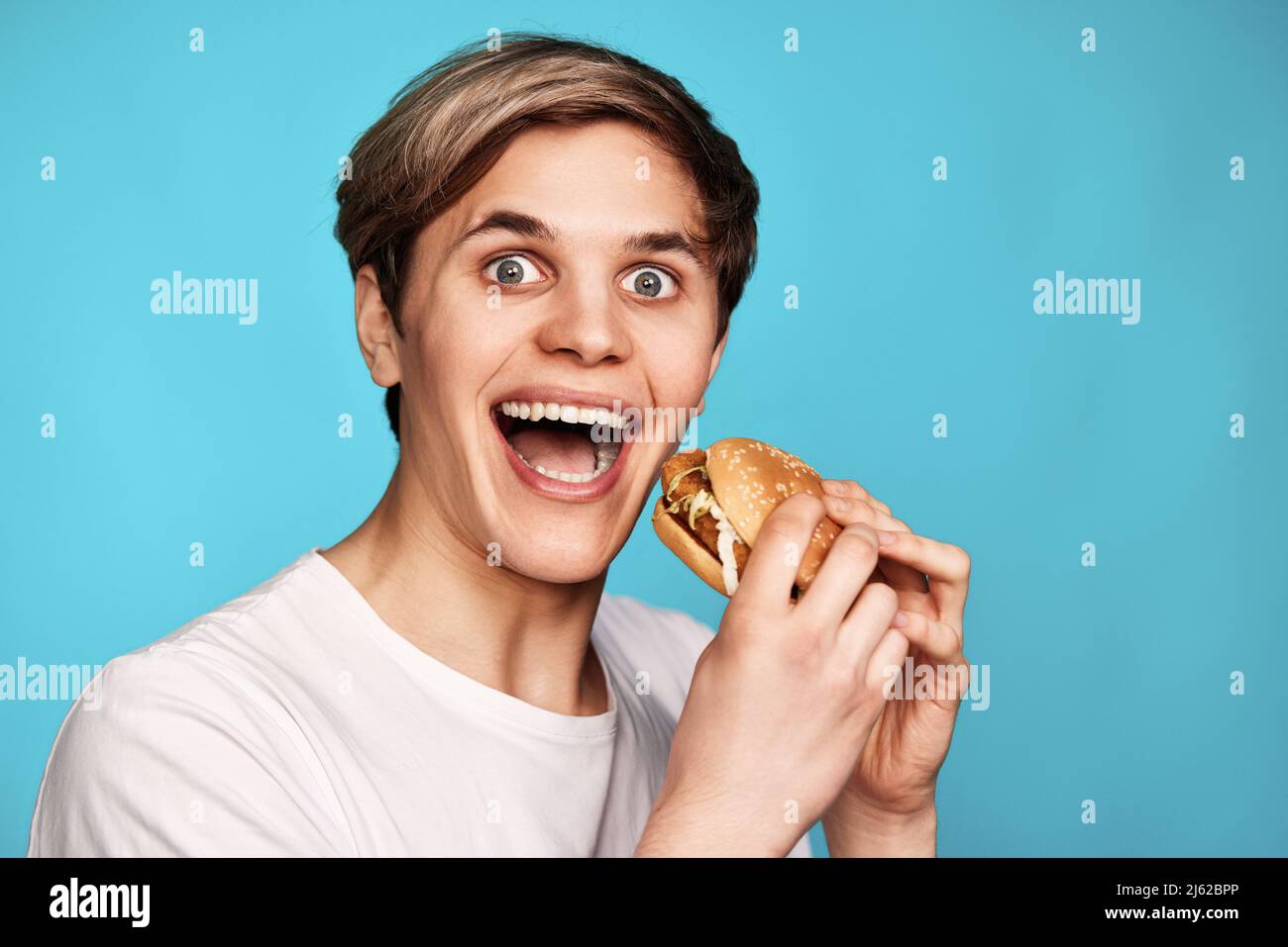 Very hungry young man holding tasty hamburger Stock Photo - Alamy