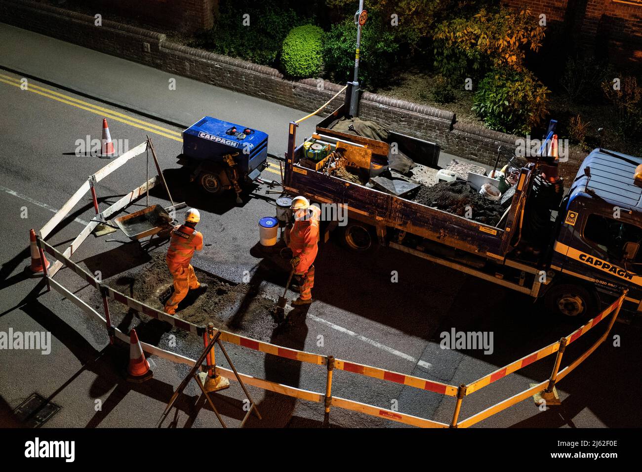 Night time roadworks, repairing a broken manhole cover in the road, in ...