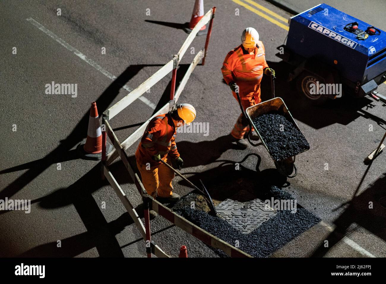 Night time roadworks, repairing a broken manhole cover in the road, in ...