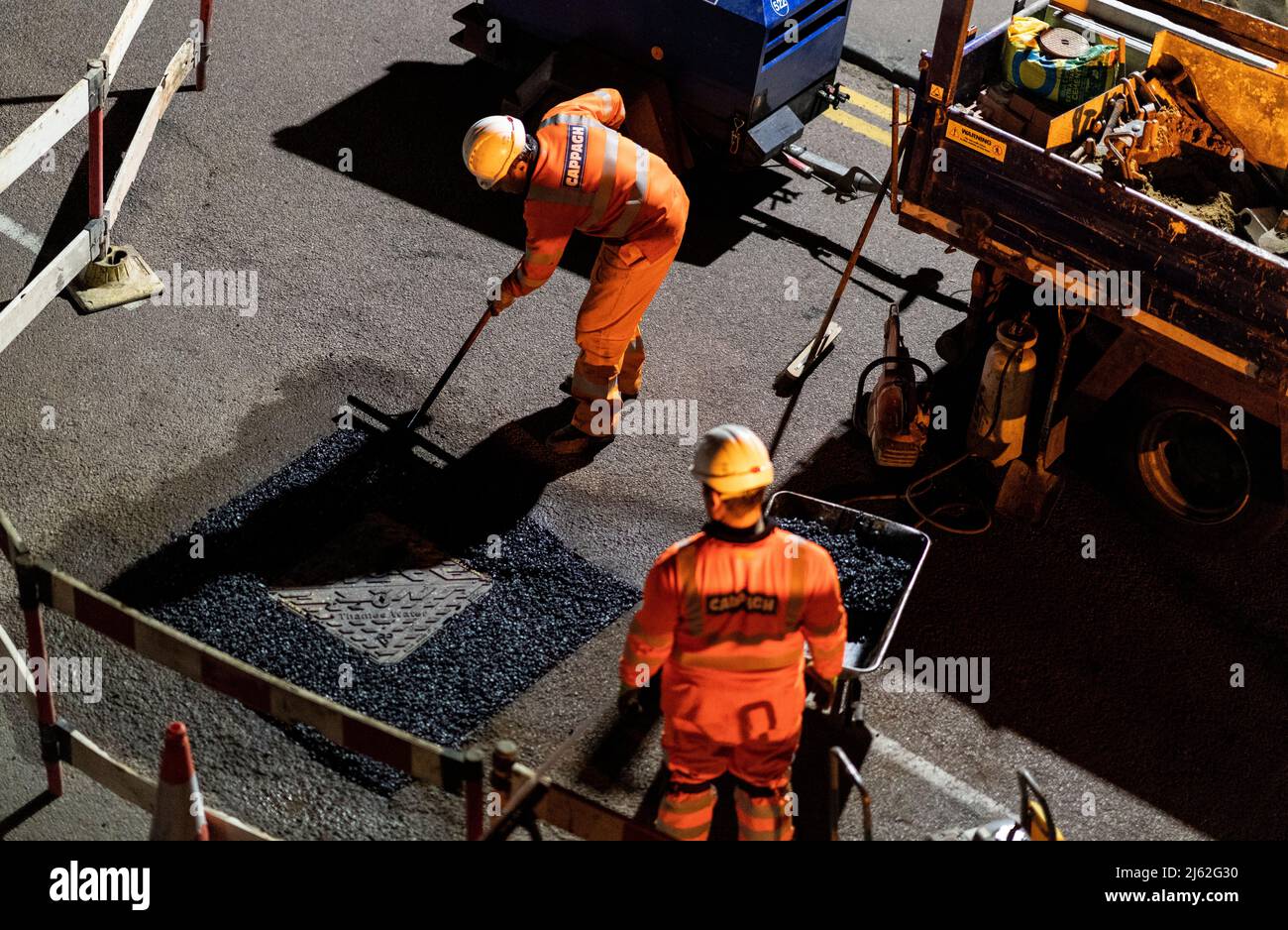 Night time roadworks, repairing a broken manhole cover in the road, in ...