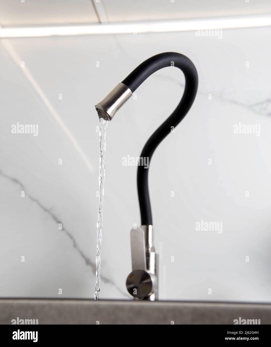 Contemporary kitchen faucet with curved spout set against white ...