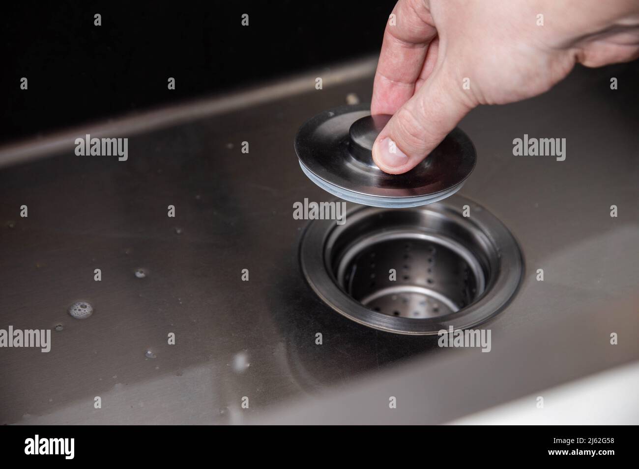 A man's hand holds a plug for a drain hole to fill water. modern ...
