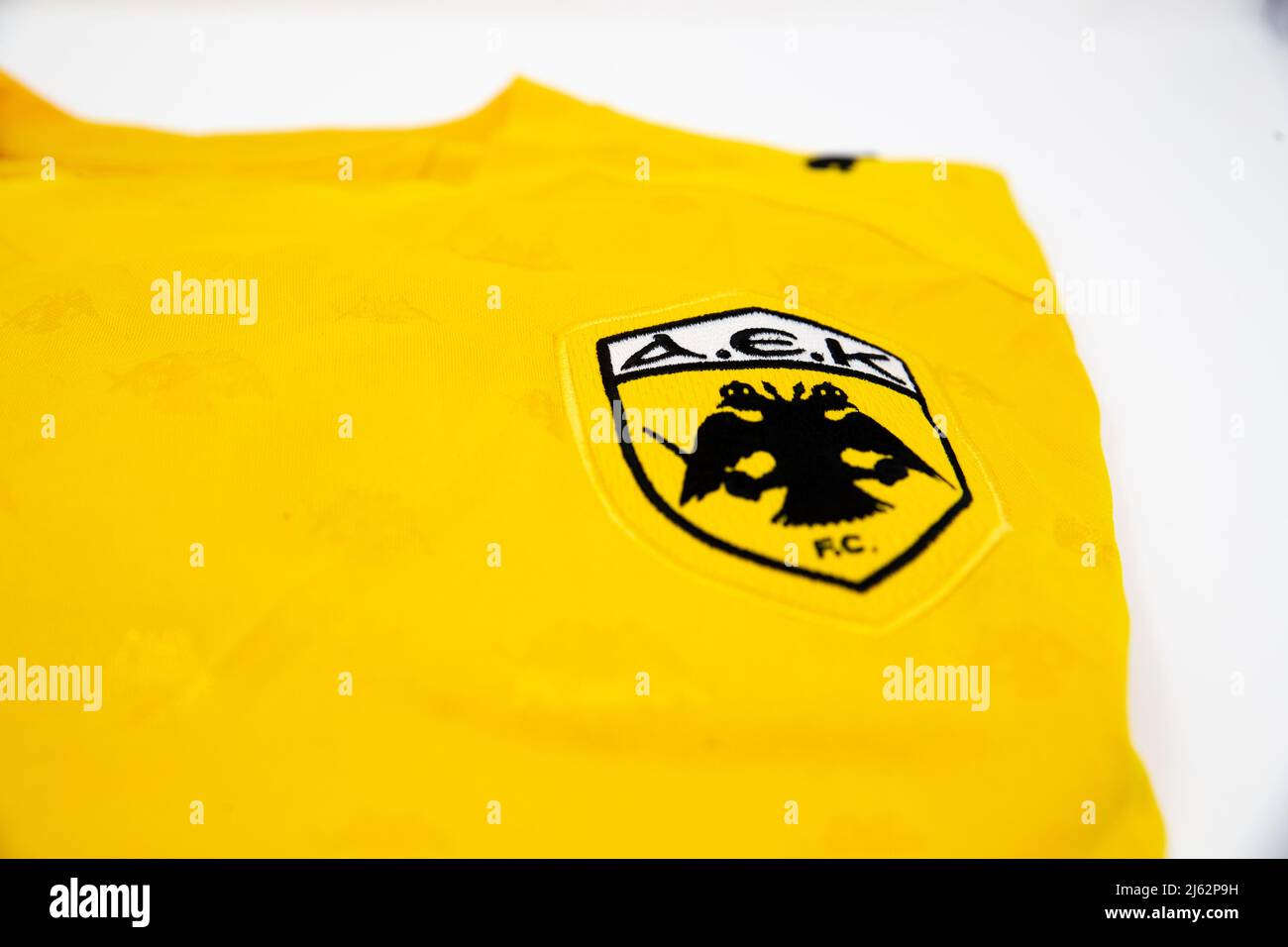AEK Athens FC badge on the front of a folded yellow puma football shirt ...