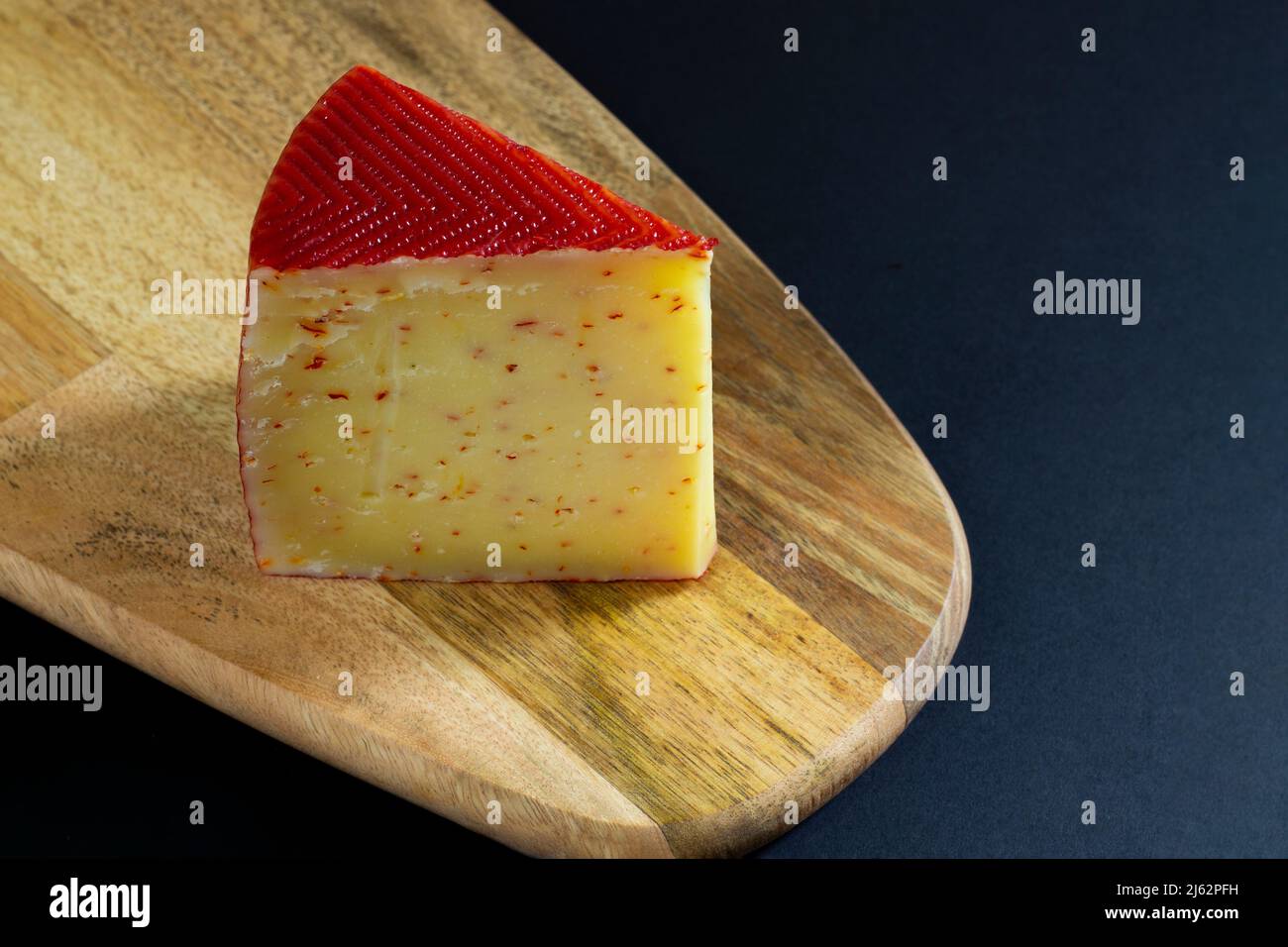 A piece of hard cheese with red pepper, spicy parmesan triangular piece ...