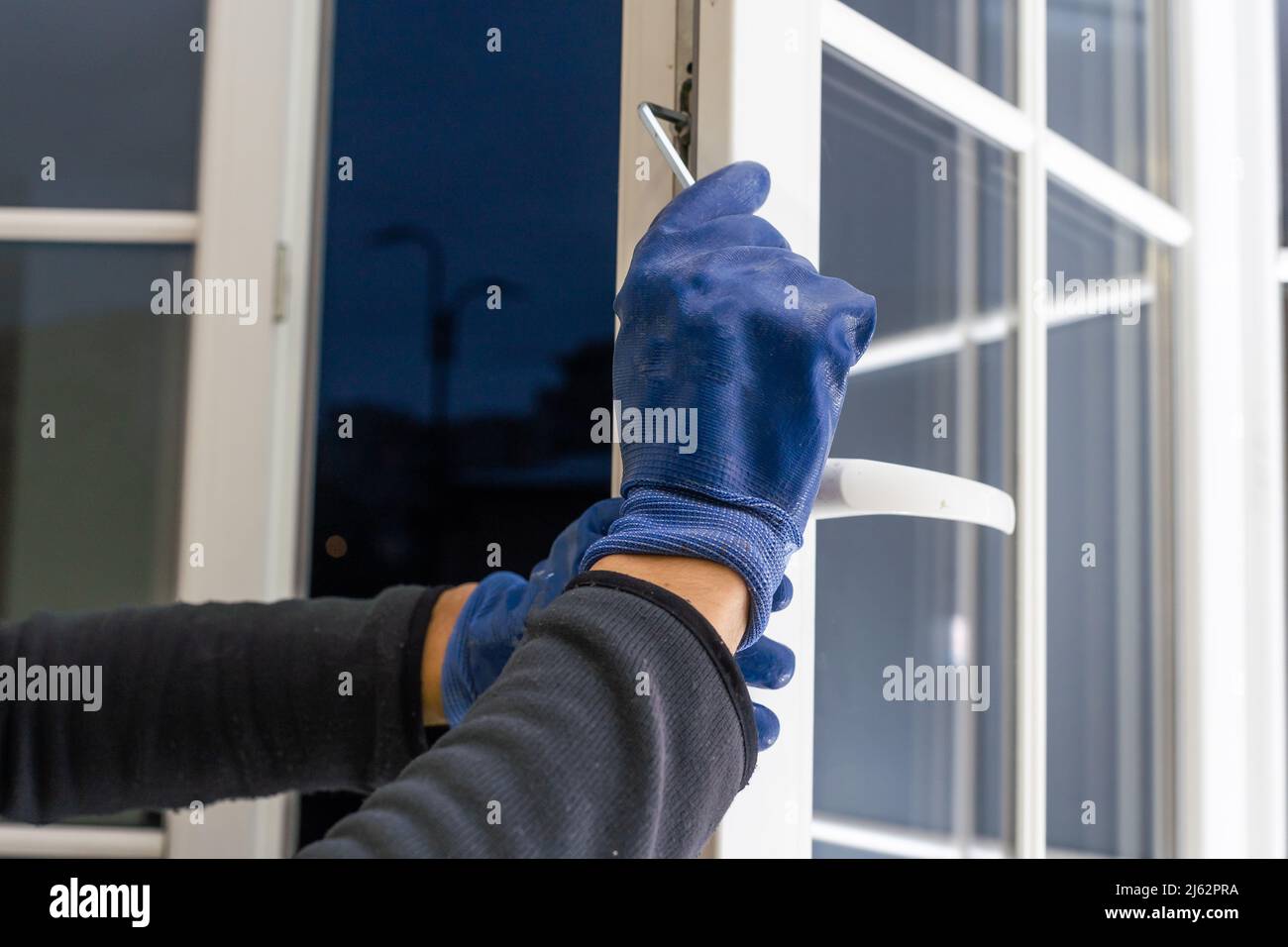 Handsome man using a screwdriver to install a window handle and looking ...