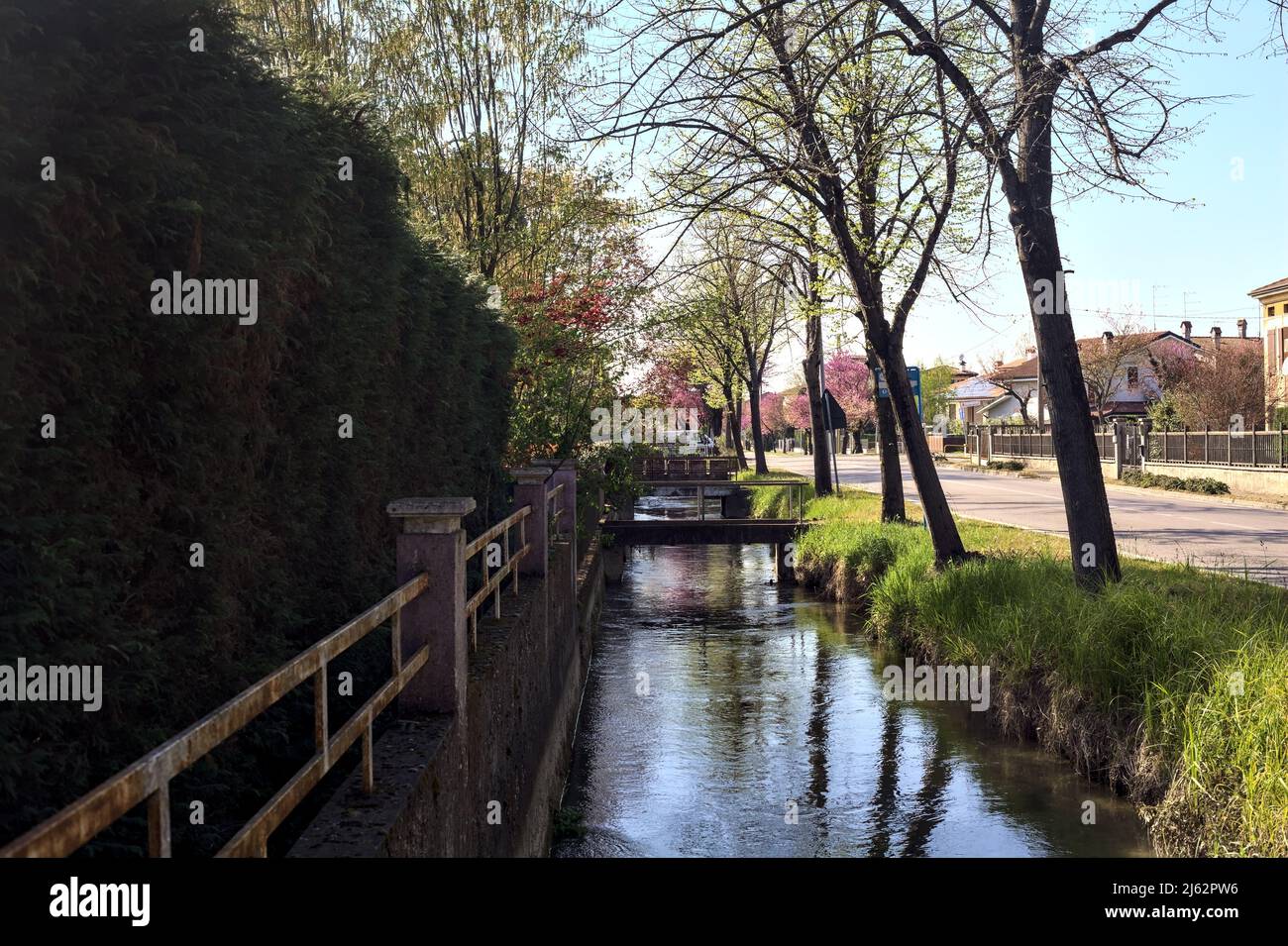 Stream of water bordered by houses and trees with reflections casted in ...