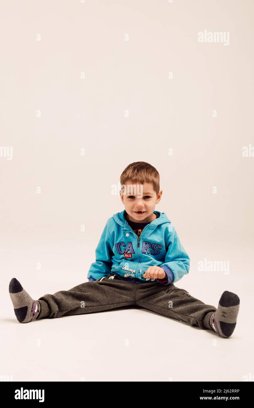 A little boy in a blue jacket sits on a white background Stock Photo ...