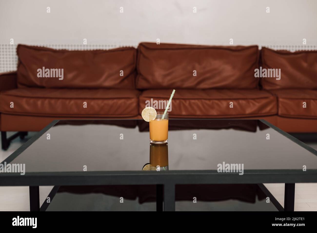 A glass of orange juice stands on a glass black table Stock Photo - Alamy