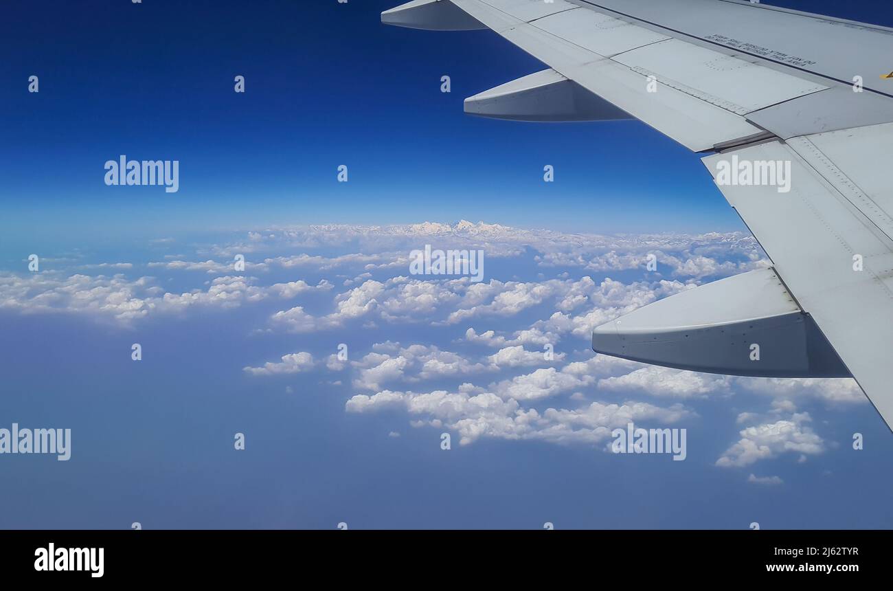 aircraft wings at mid air with low clouds and bright blue sky ...