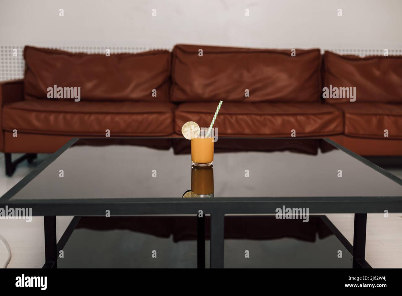 A glass of orange juice stands on a glass black table Stock Photo - Alamy