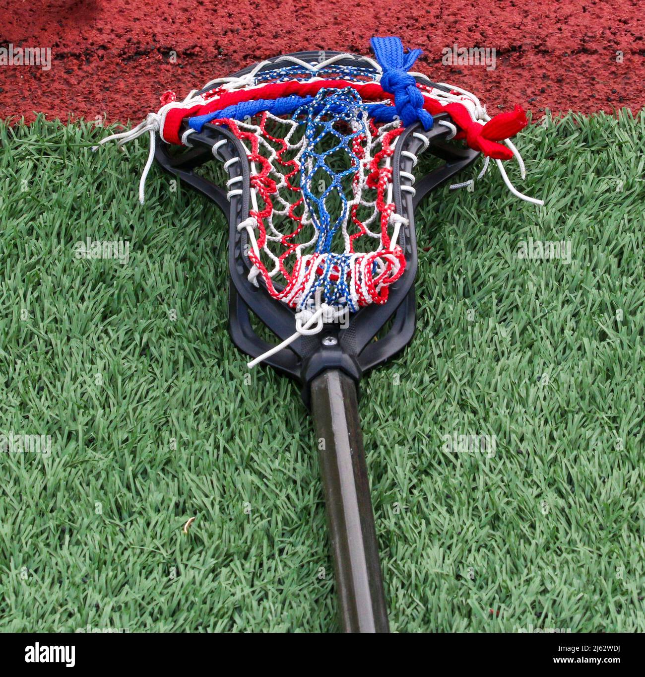 One lacrosse stick on the ground with red white and blue netting Stock ...