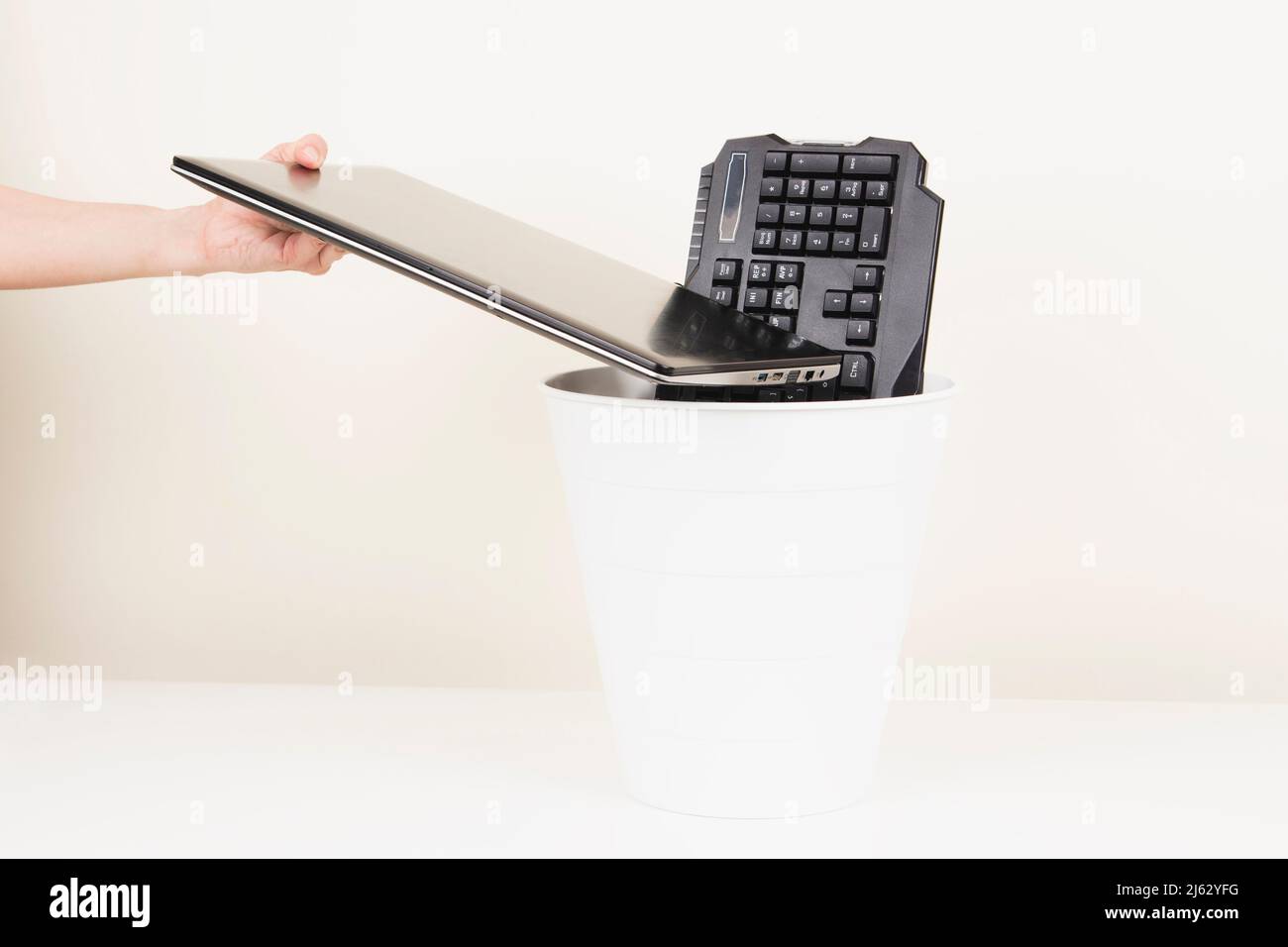 Hand puts used laptop computer into recycling bin full of old ...