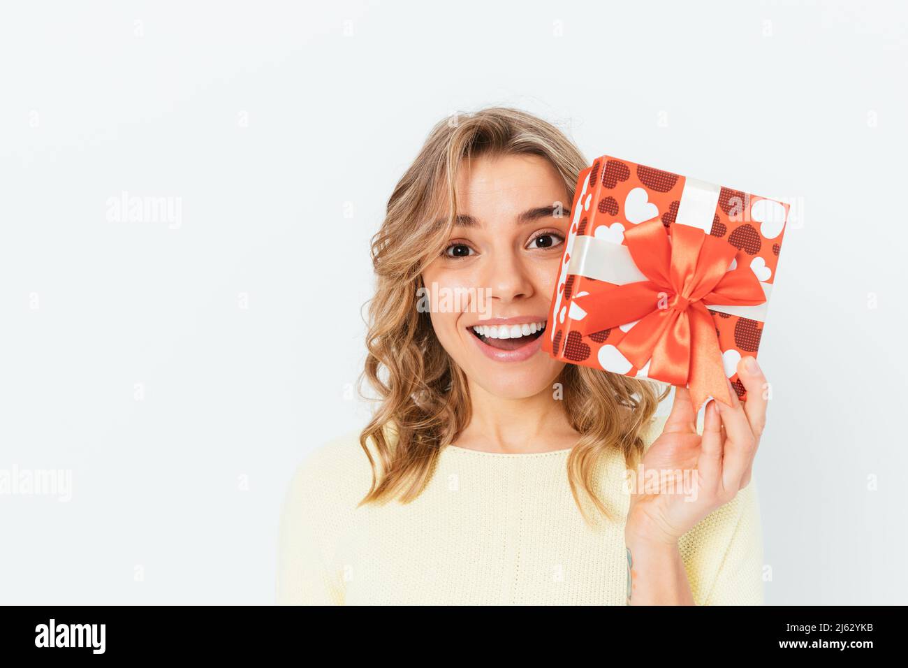 Portrait pleased smiling young woman holding gift box standing on white ...