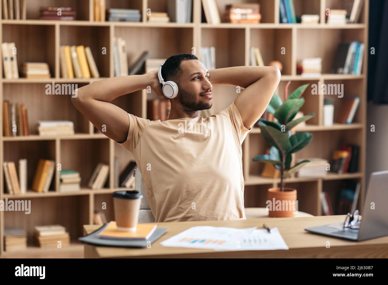 Relaxed arab man listening to music in headphones, resting with hands ...