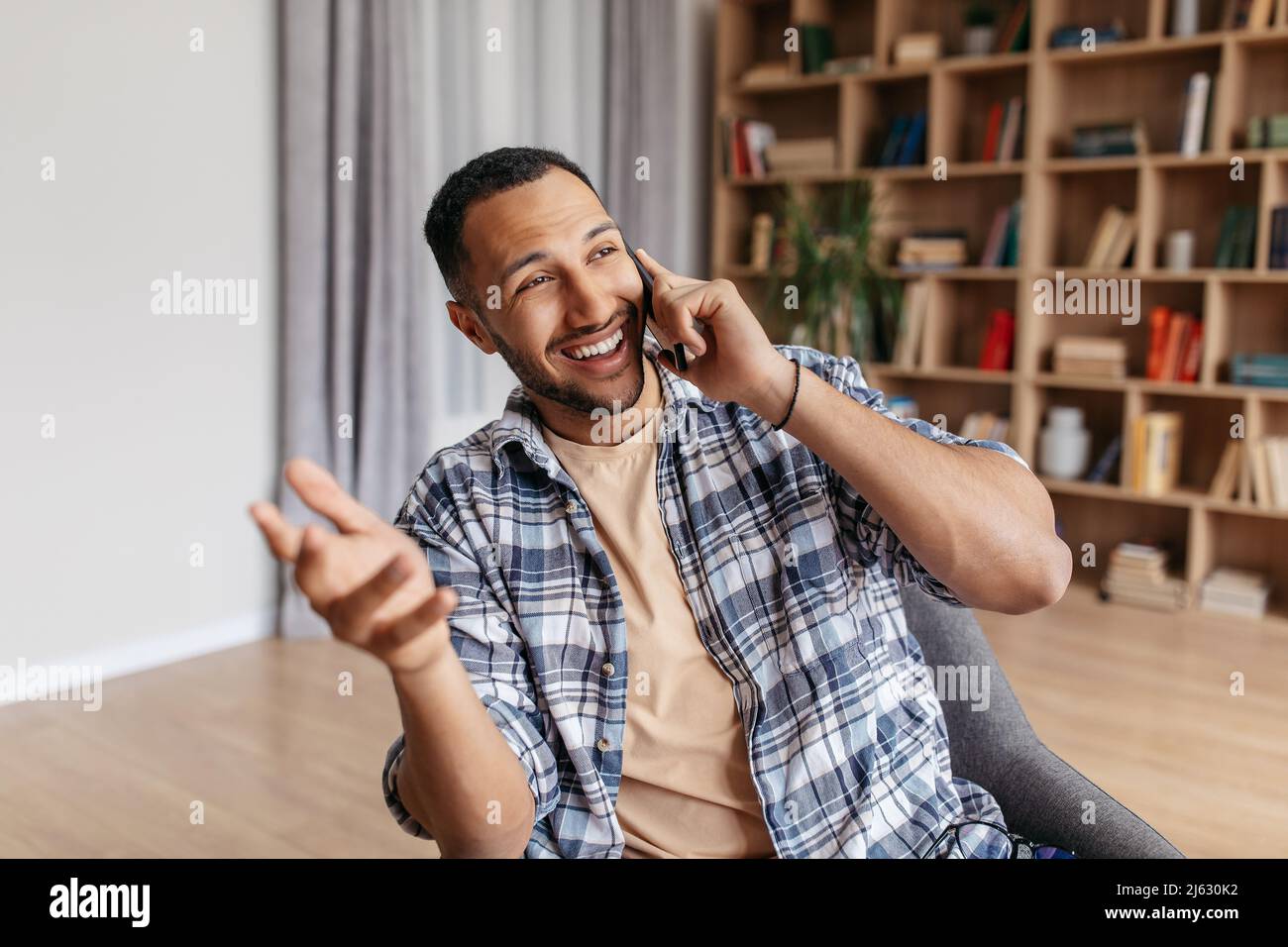 Excited middle eastern man talking emotionally on cellphone, sitting in ...