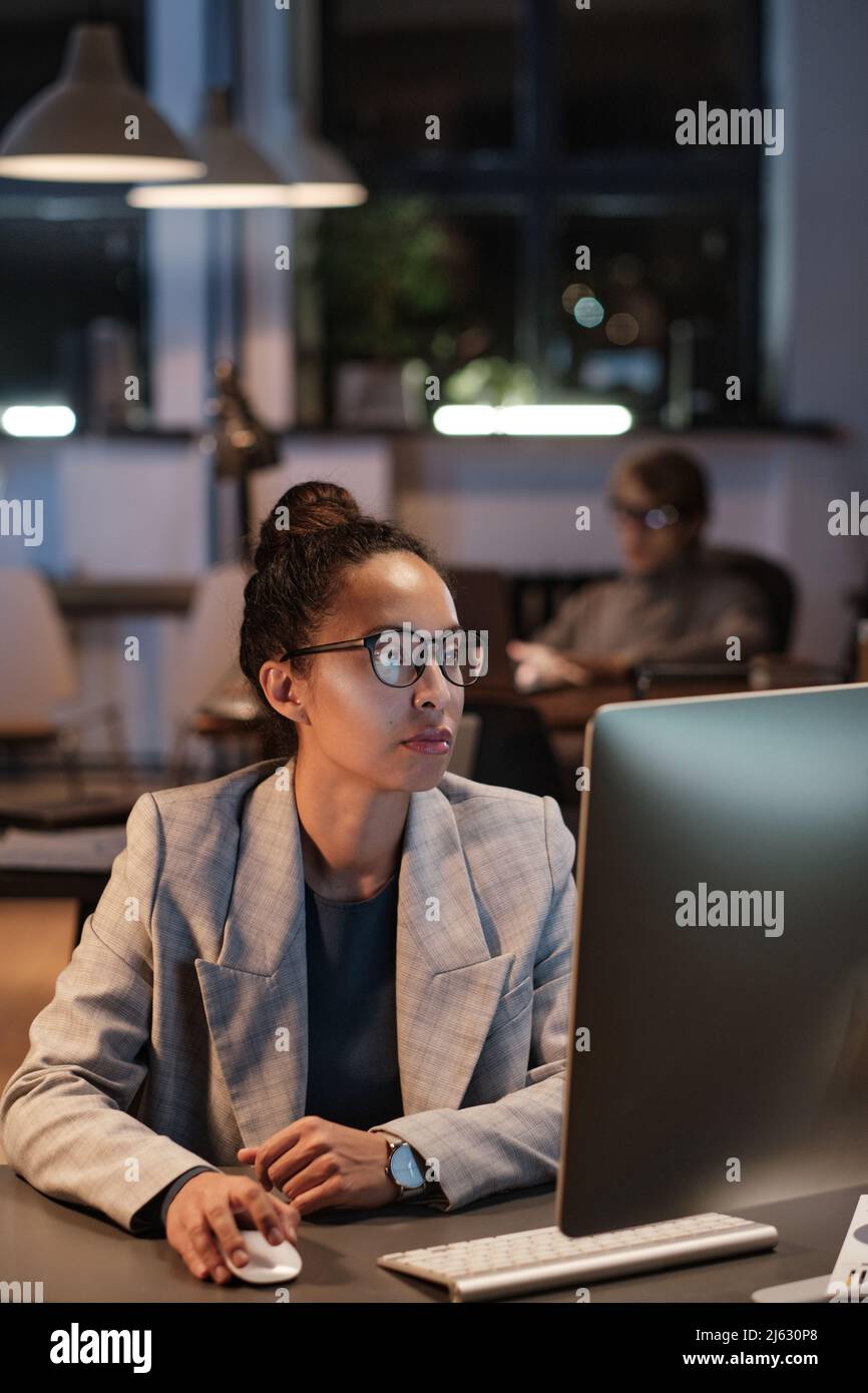 Serious focused young mixed race company manager in eyeglasses using ...