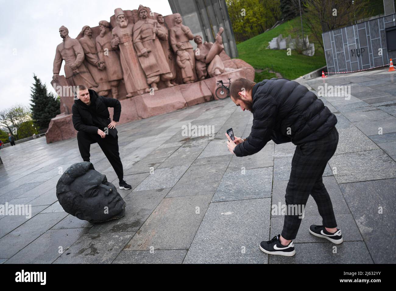 A man poses for photos while stepping on the dismantled Soviet Union ...