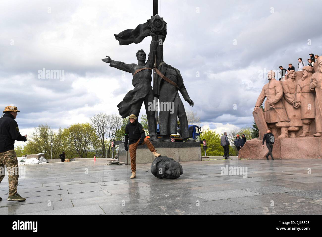 A man poses for photos while stepping on the dismantled Soviet Union ...
