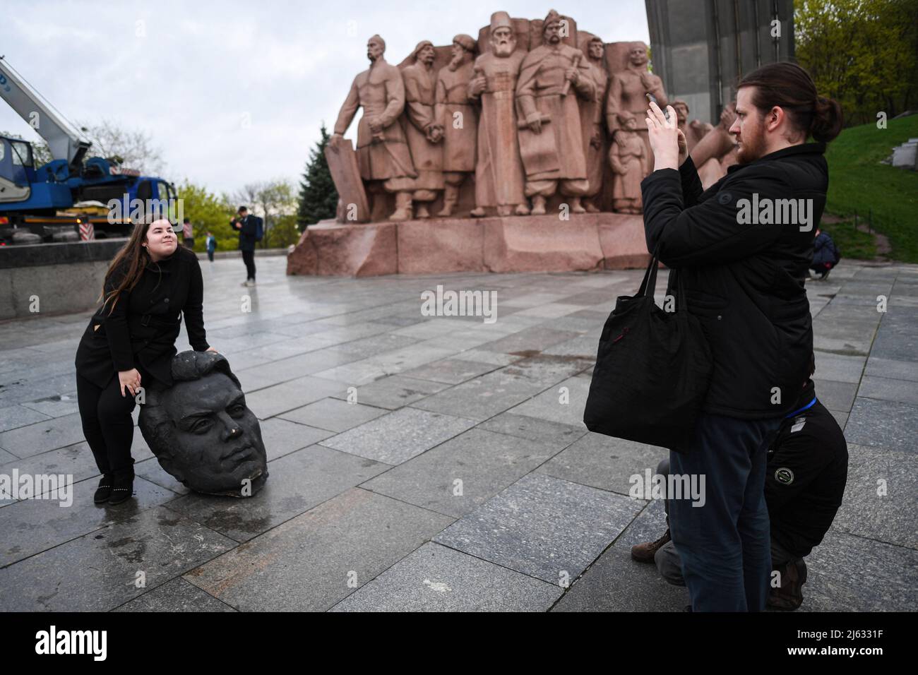 A woman poses for photos with the dismantled Soviet Union monument. On ...