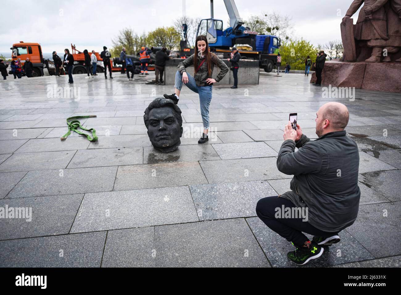 A woman poses for photos while stepping on the dismantled Soviet Union ...