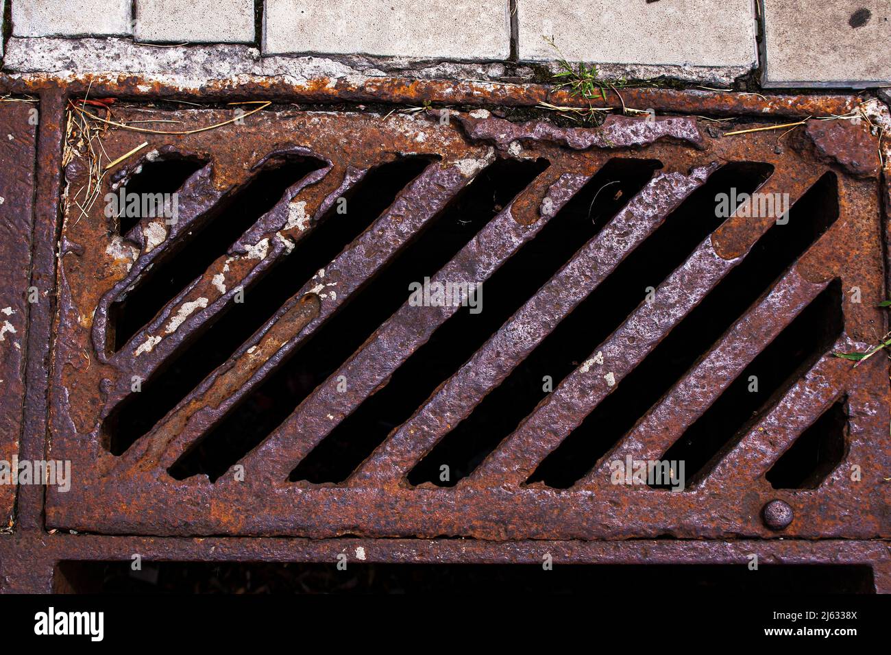 An old rusty manhole for receiving rainwater or melted snow. Against ...